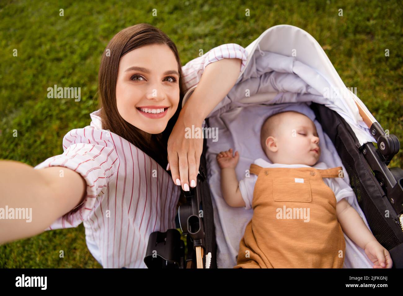 Photo of charming cute positive mommy blogger walk sleeping infant kid ...