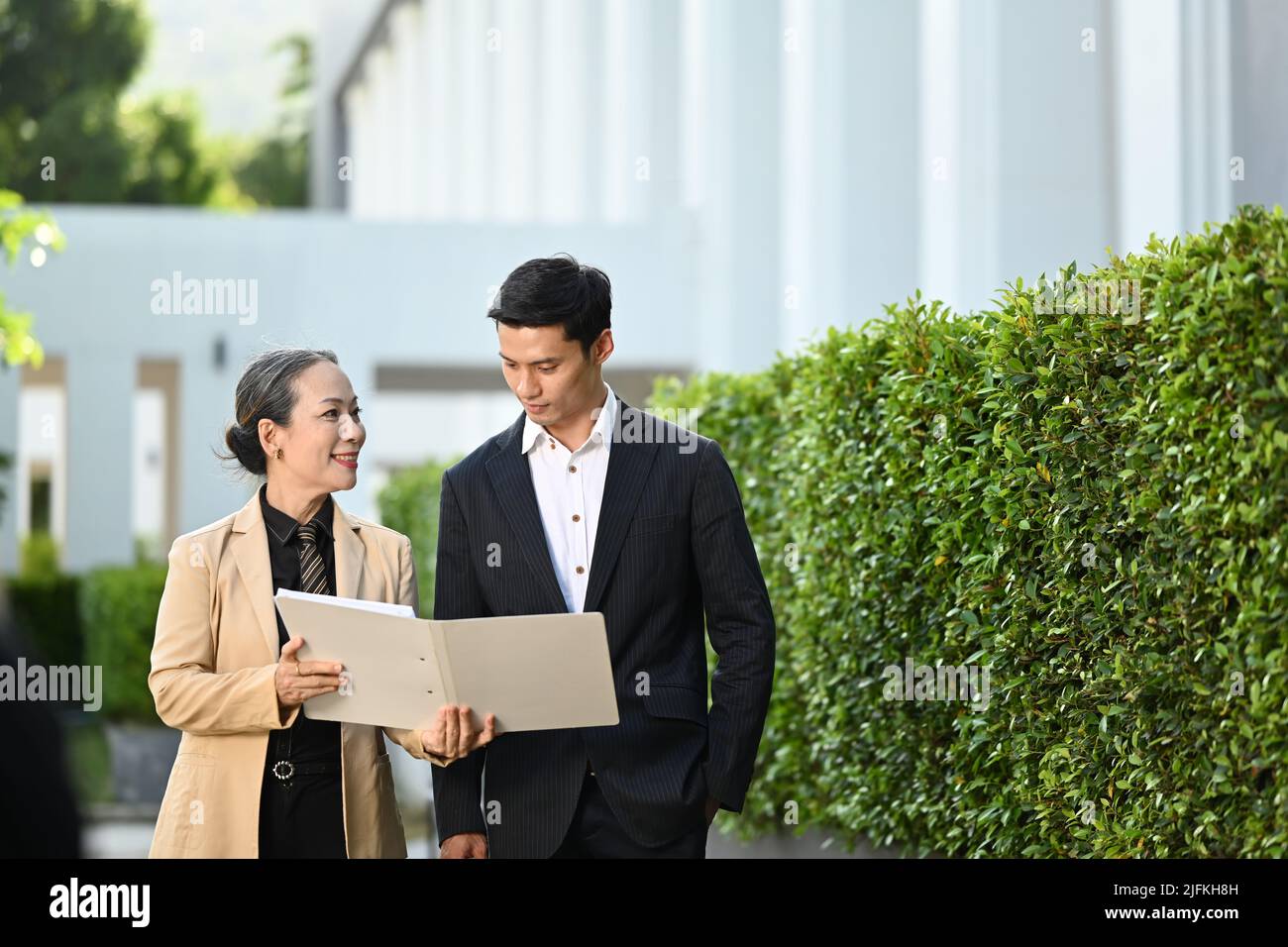 Two successful business people having a discussion while walking ...