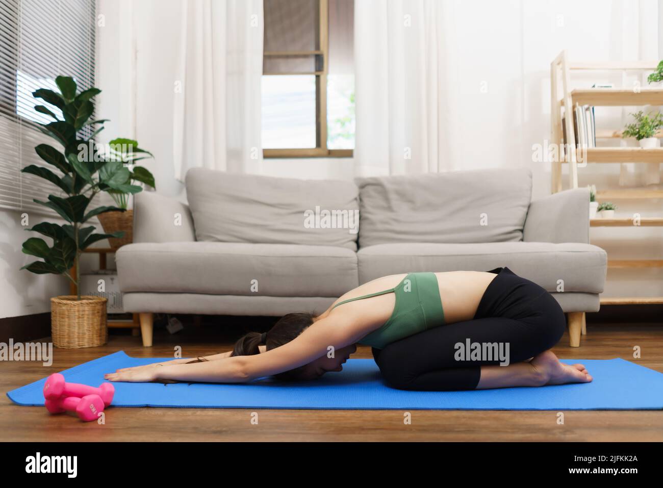 Yoga and wellness concept, Young Asian woman doing yoga to lying in child pose on mat at home ...