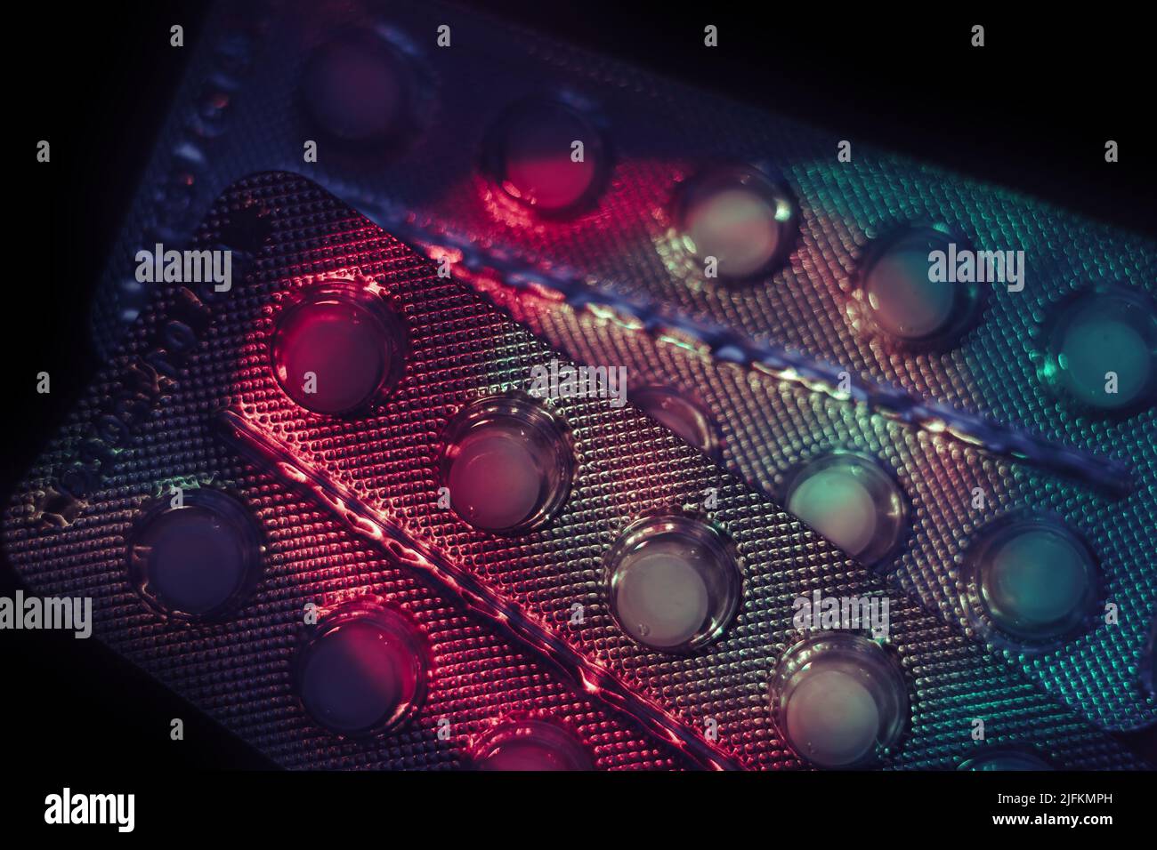 Pills or drugs in a package under neon light on a dark background ...