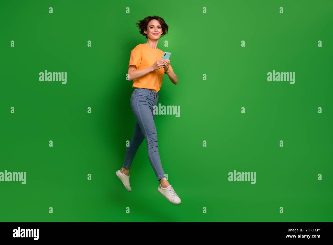 Full length portrait of energetic pretty girl arms hold telephone jump ...