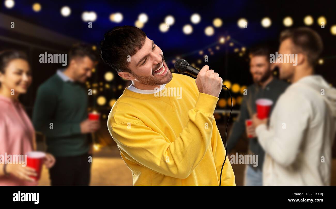 man with microphone singing at night rooftop party Stock Photo - Alamy
