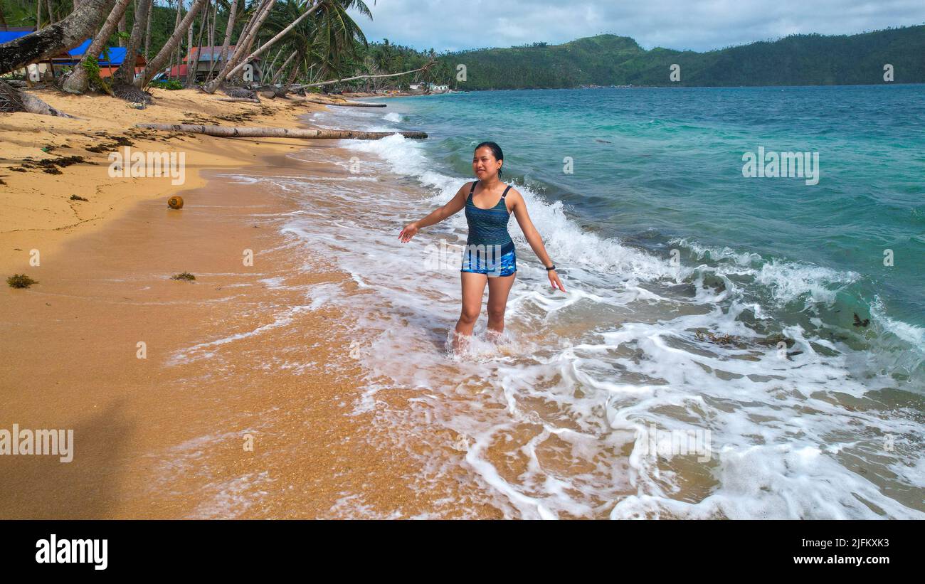 A South Asian woman posing on a beach, standing in sea waves in ...