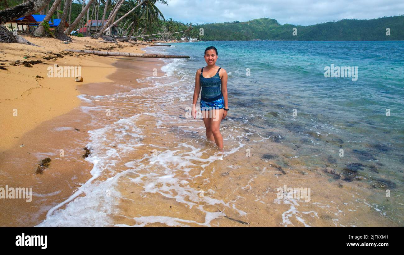 A South Asian woman posing on a beach, standing in sea waves in ...