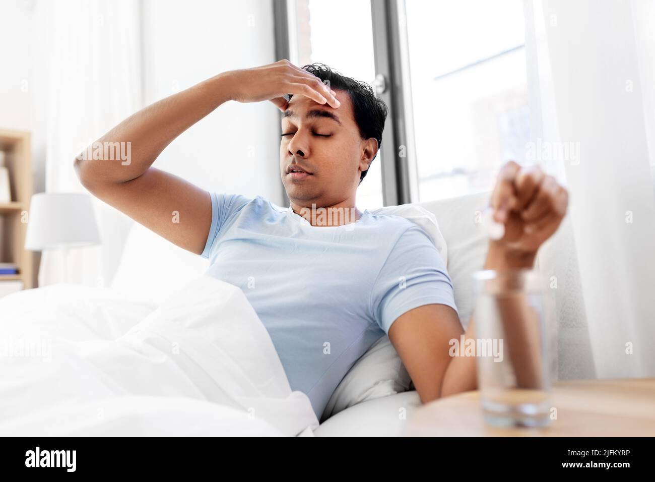sick man in bed with medicine and glass of water Stock Photo - Alamy