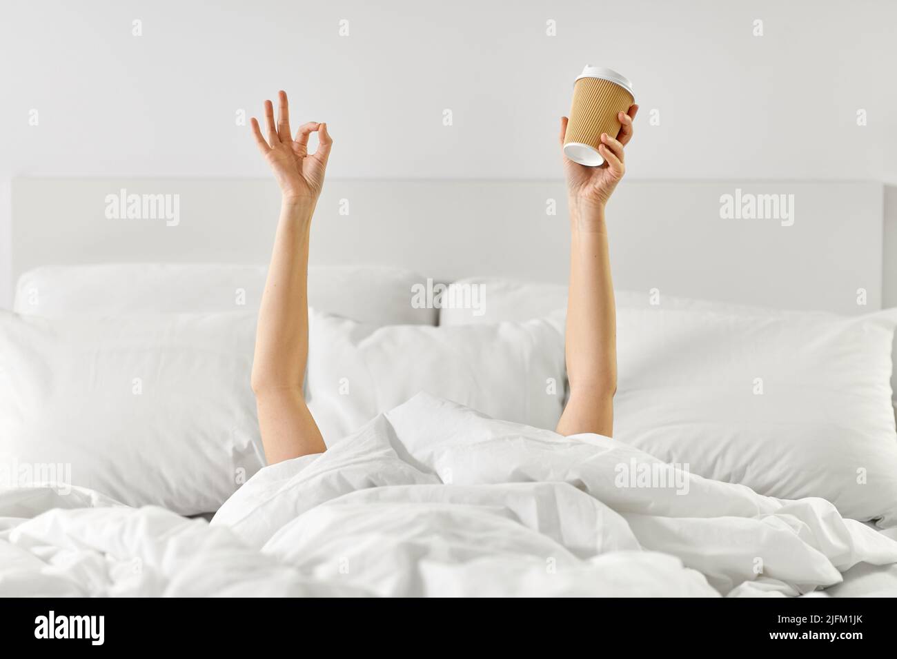 woman with cup of coffee lying in bed showing ok Stock Photo - Alamy
