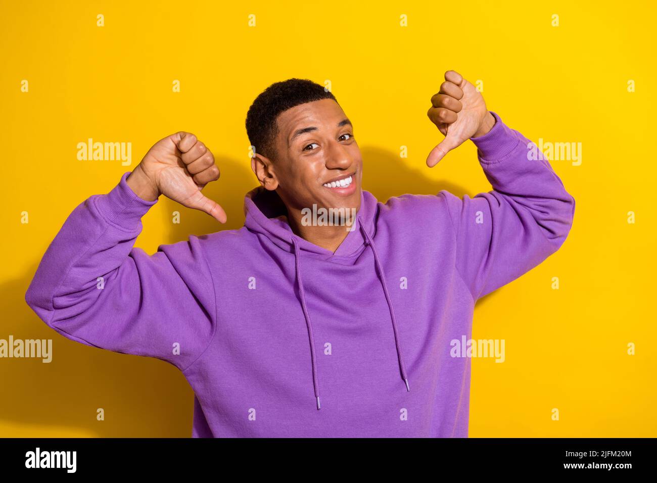 Photo of young positive millennial guy showing his cool violet hoodie ...
