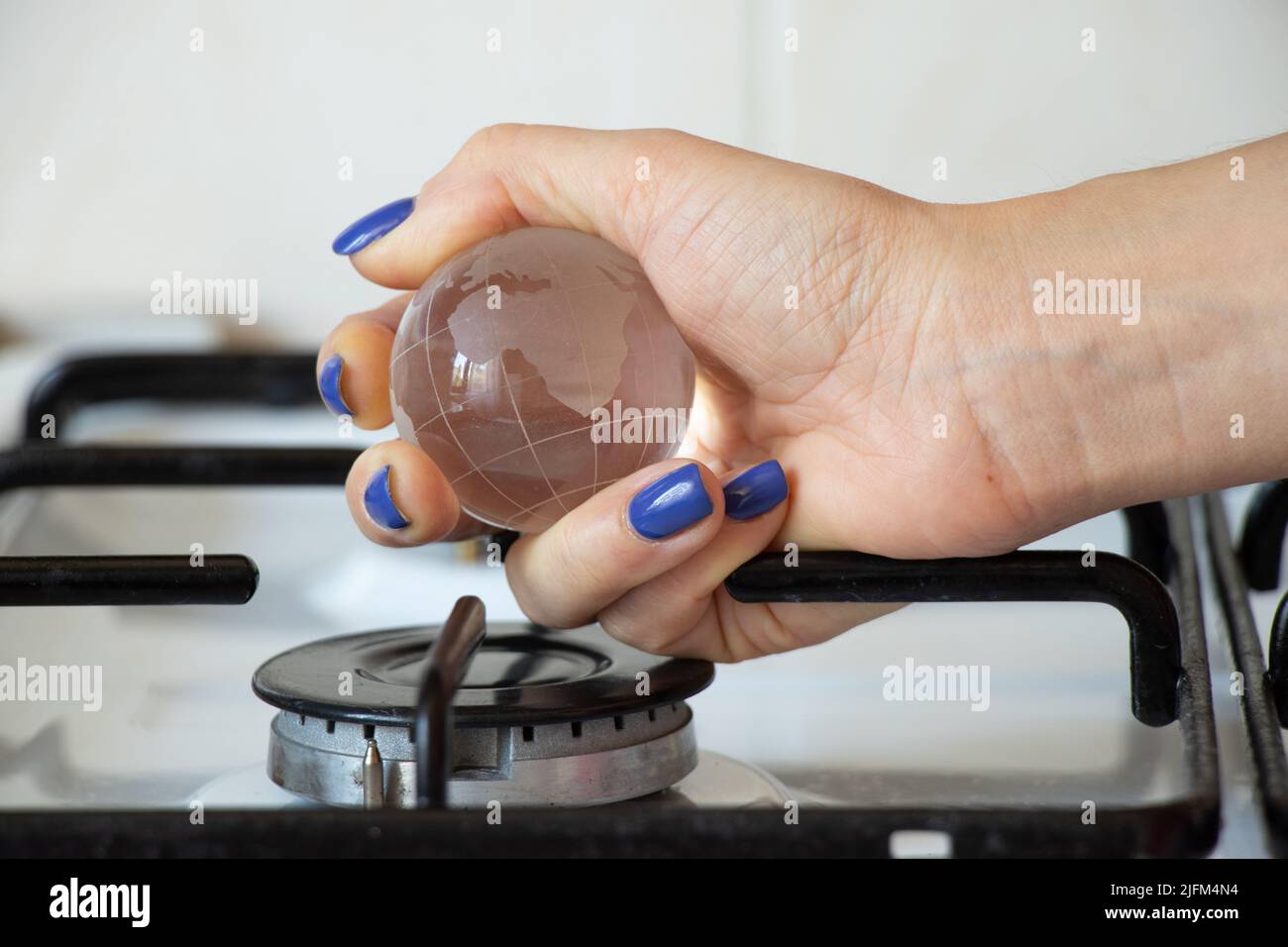 A woman's hand holds a small ball of earth over a gas burner at home, a ...