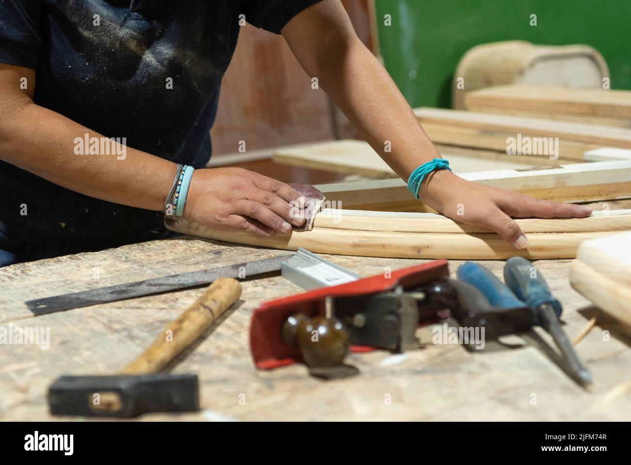 Hands of a female carpenter sanding wood with sandpaper to give it a ...