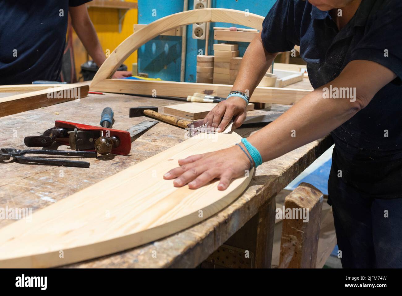 Hands of a female carpenter sanding wood with sandpaper to give it a ...