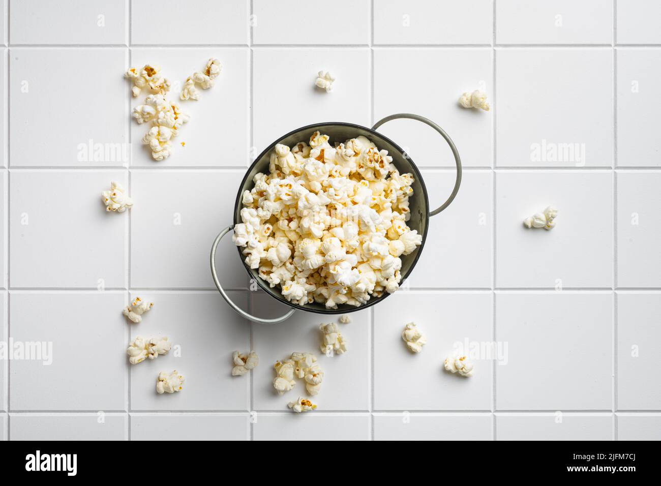 Salted popcorn on white ceramic squared tile table background, top view ...
