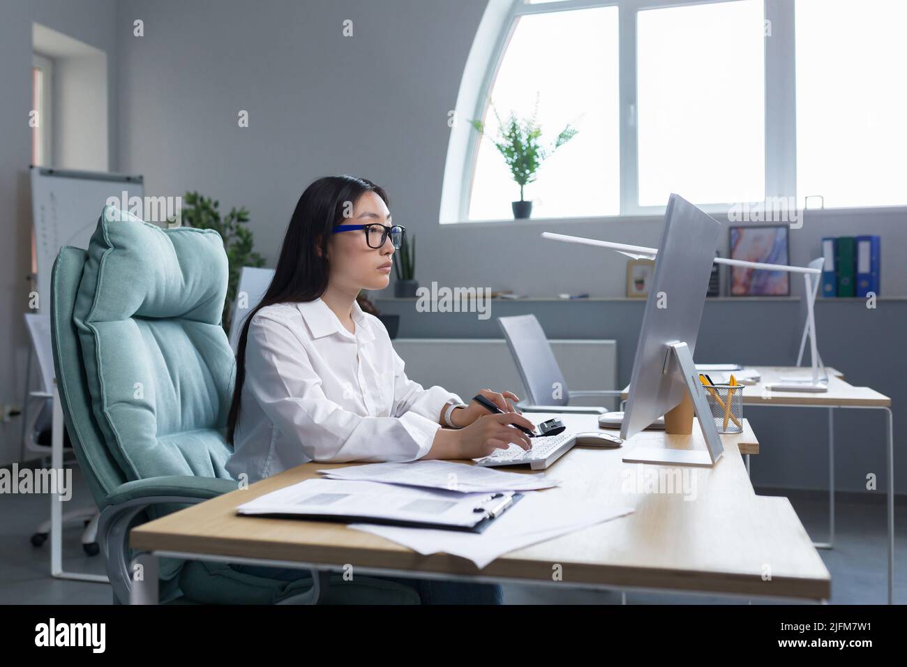 Asian successful business woman working with computer in modern office ...
