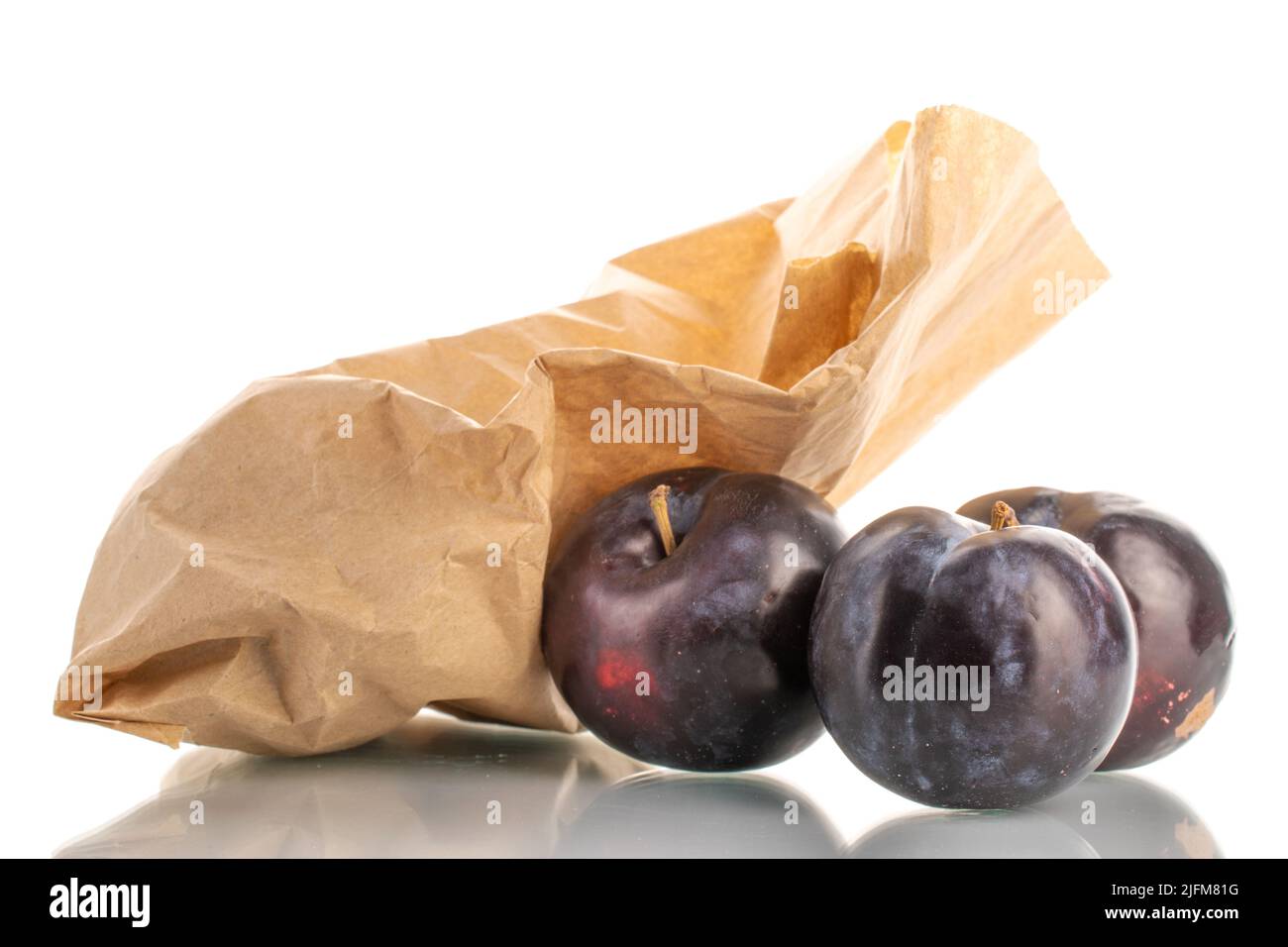 Three dark blue organic plums with a package of paper, close-up ...
