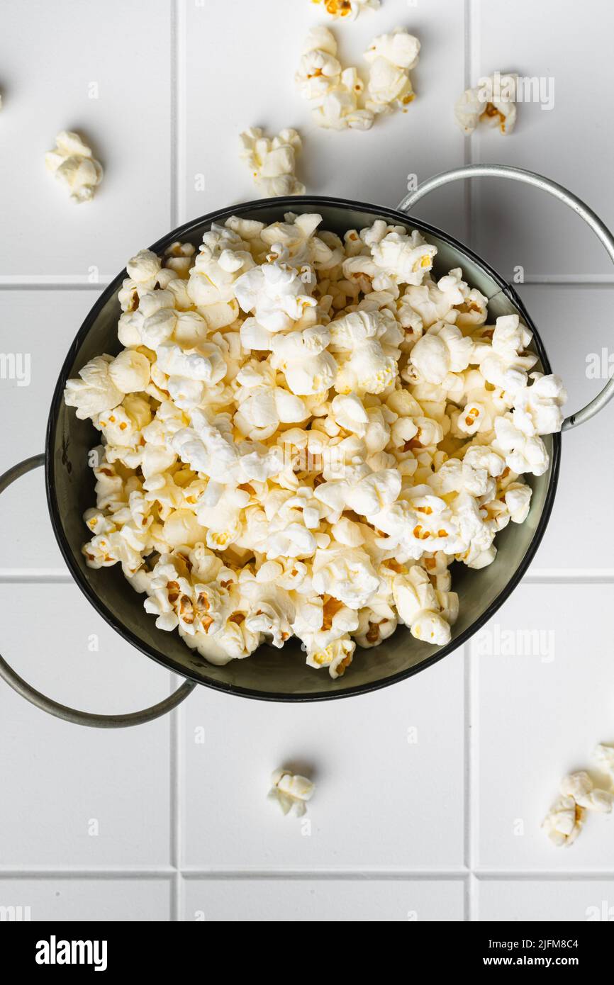 Prepared salted popcorn on white ceramic squared tile table background ...