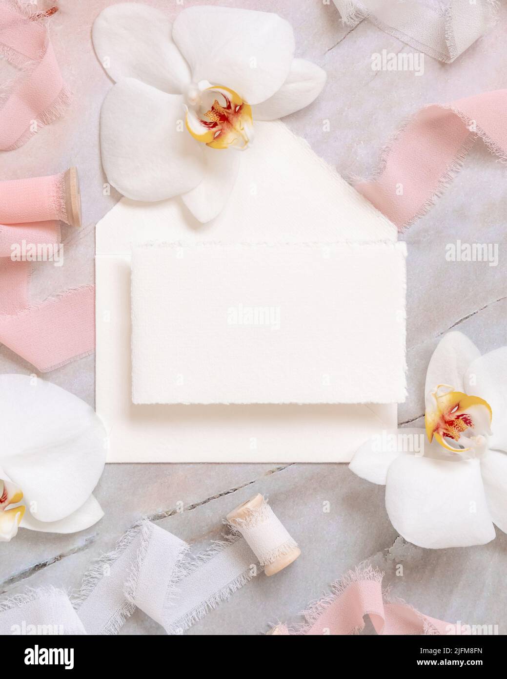 Wedding horizontal card and envelope near white orchid flowers and silk ...