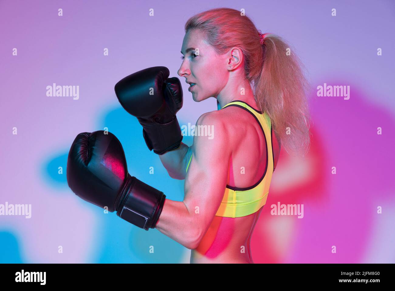 Energetic young woman, female professional kickboxer in sports uniform ...