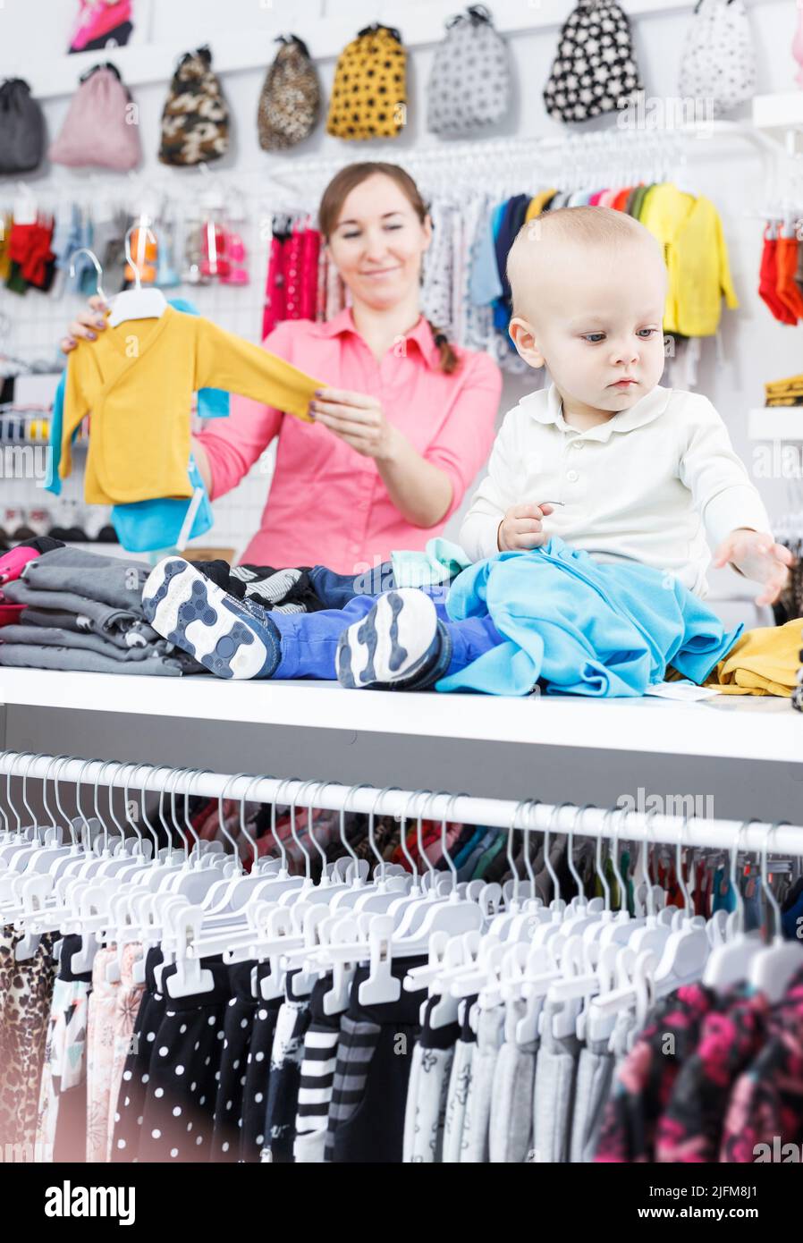 kid who is posing when his mother choosing clothes Stock Photo - Alamy