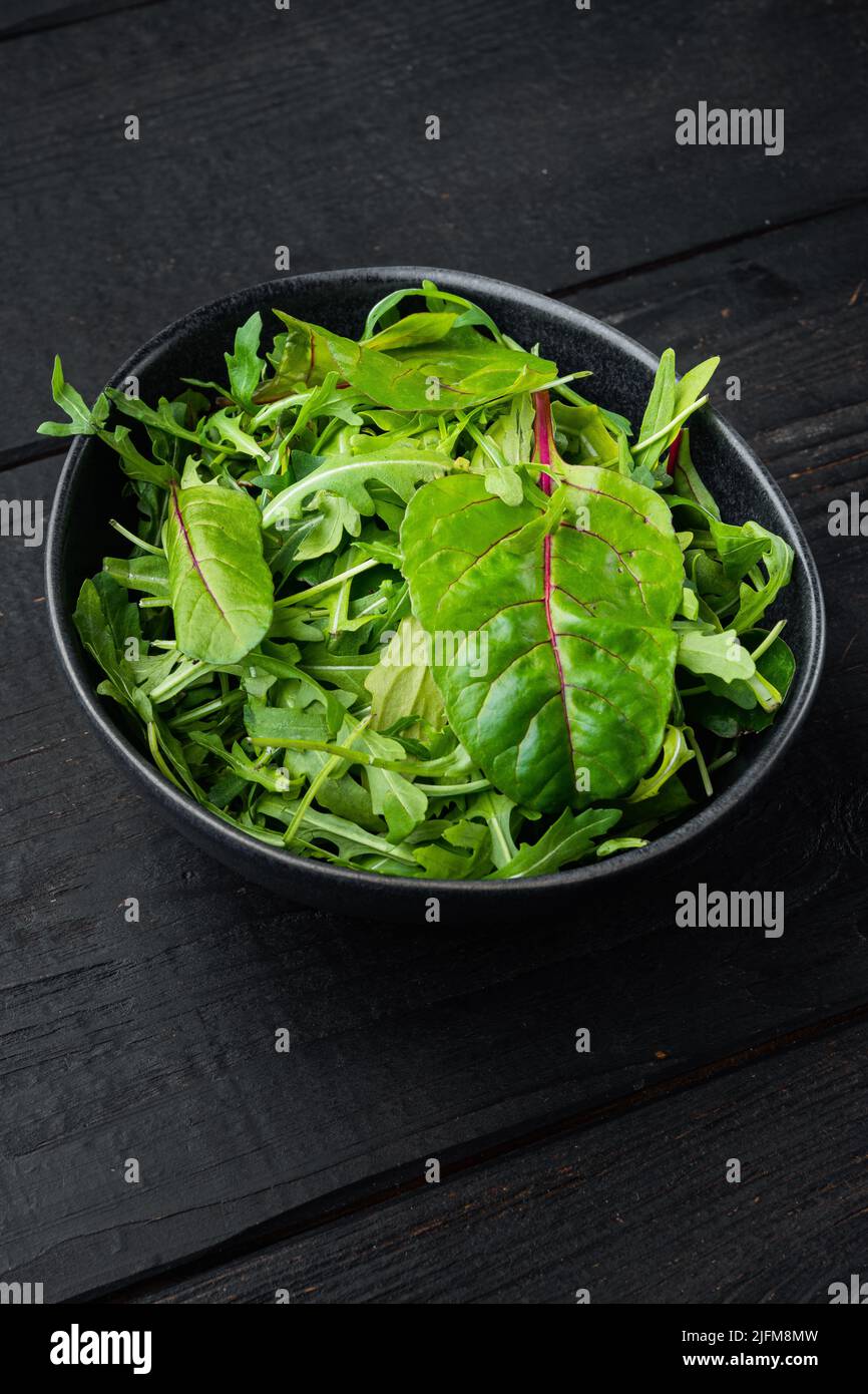 Herb green salad with arugula and Mangold, Swiss chard, on black wooden ...