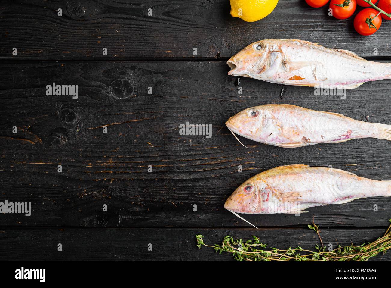 Raw Goatfish fresh whole fish, with ingredients and herbs, on black ...