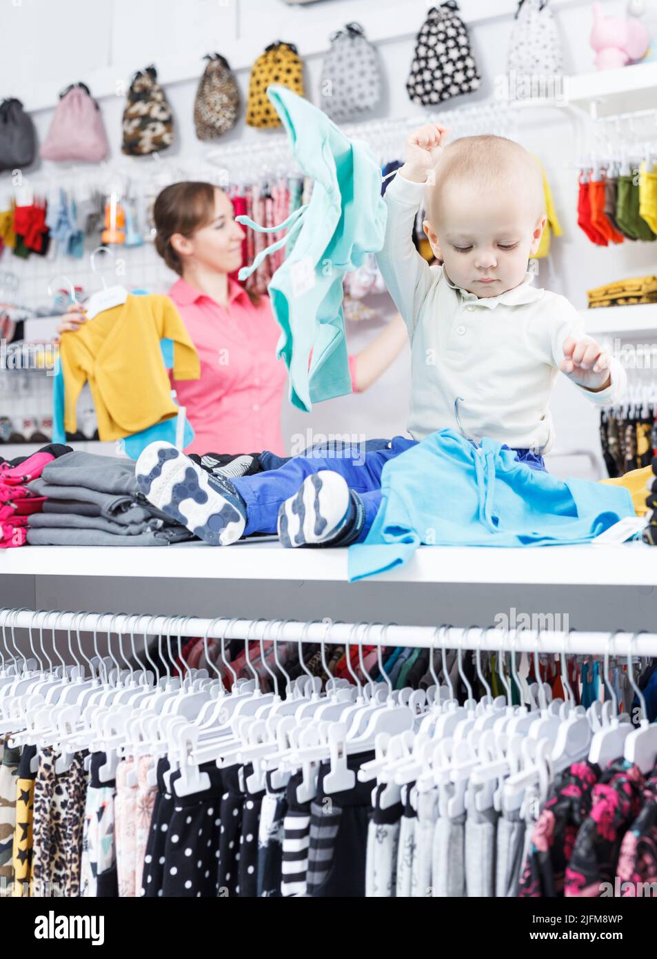 kid who is posing when his mother choosing clothes Stock Photo - Alamy