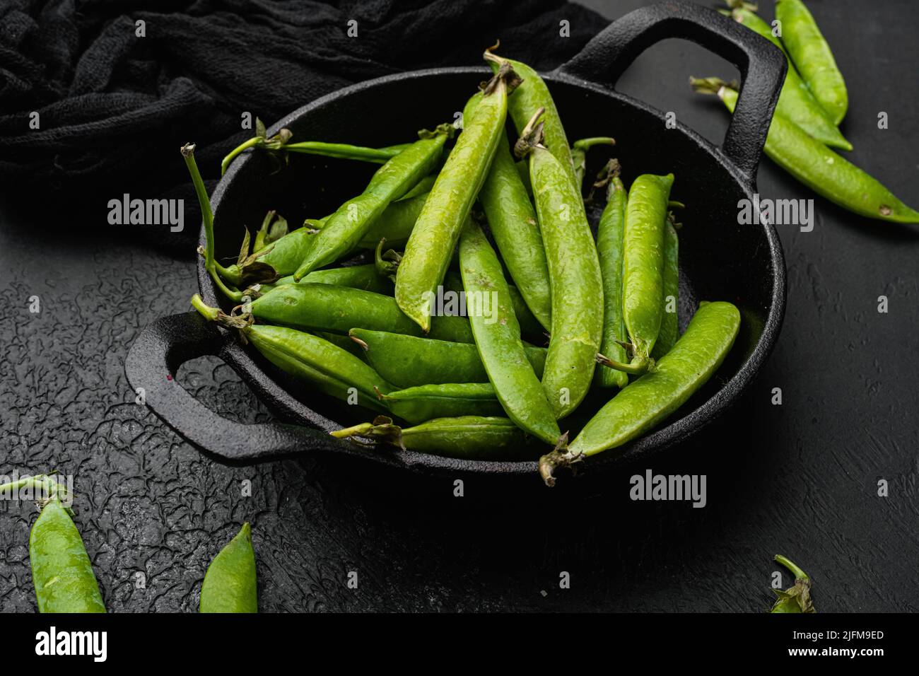 Raw Green Organic Snow Peas on black dark stone table background Stock ...