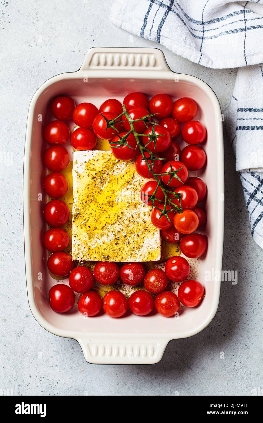 Baked feta cheese with tomatoes in a dish, top view. Cooking trendy ...