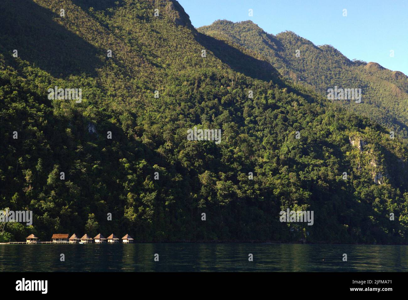 Coastal landscape of Seram Island with wooden cottages above sea water ...