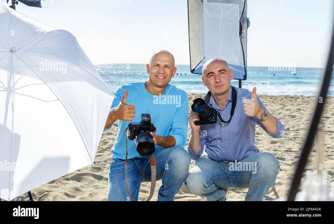 two photographers with their cameras during professional photo shooting ...