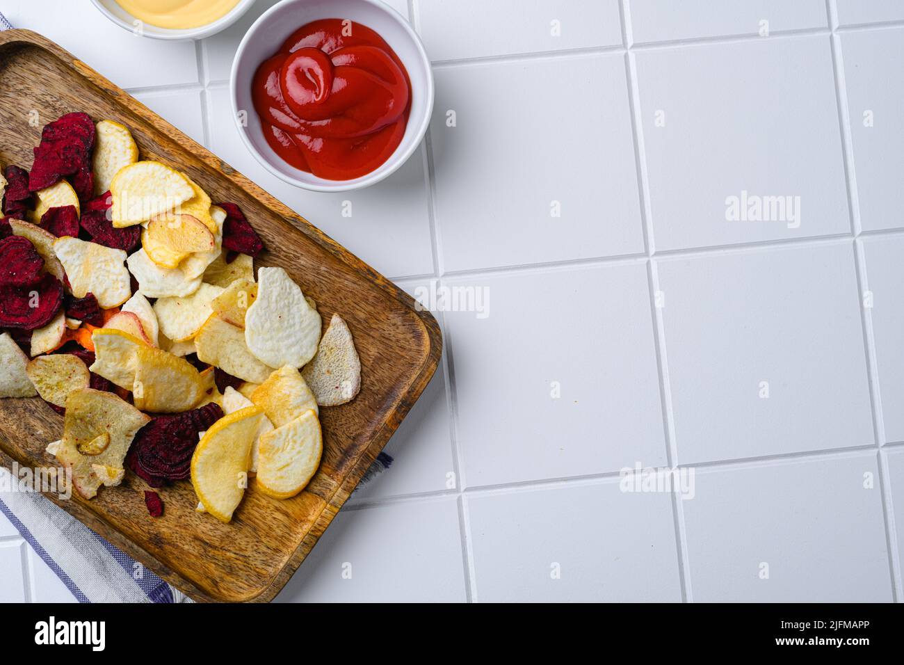 Root Vegetable Crisps, on white ceramic squared tile table background ...