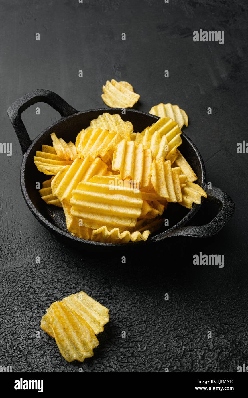 Wavy Lightly Salted Potato Chips on black dark stone table background ...