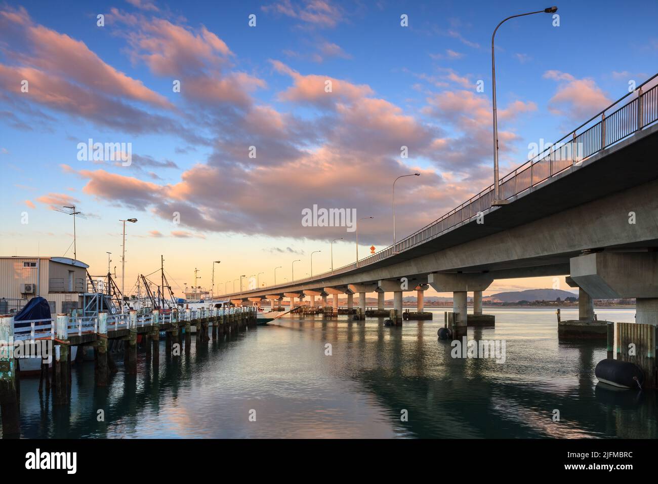 The harbour bridge in Tauranga, New Zealand, at sunset. On the left is ...