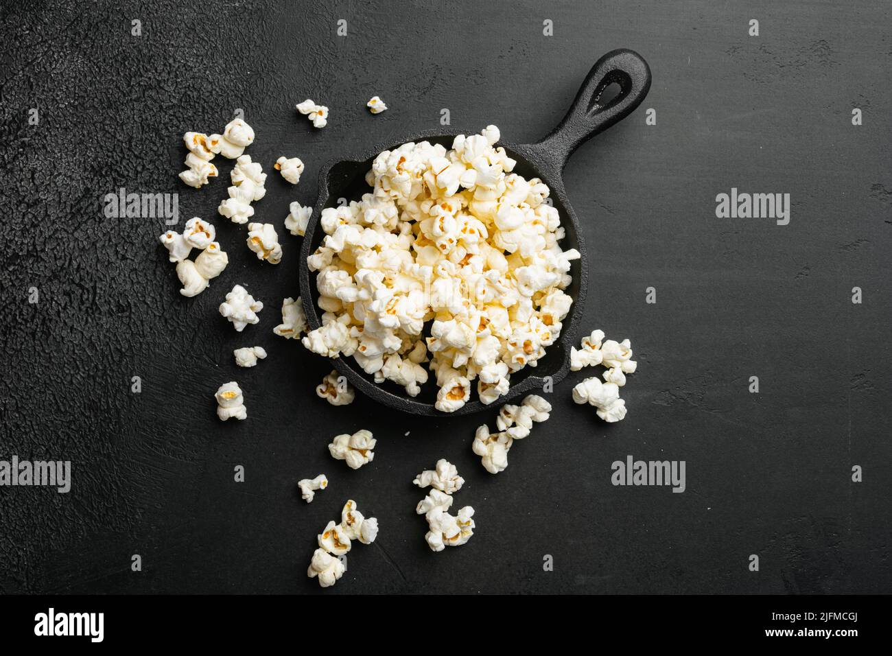 Heap of delicious popcorn on black dark stone table background, top ...