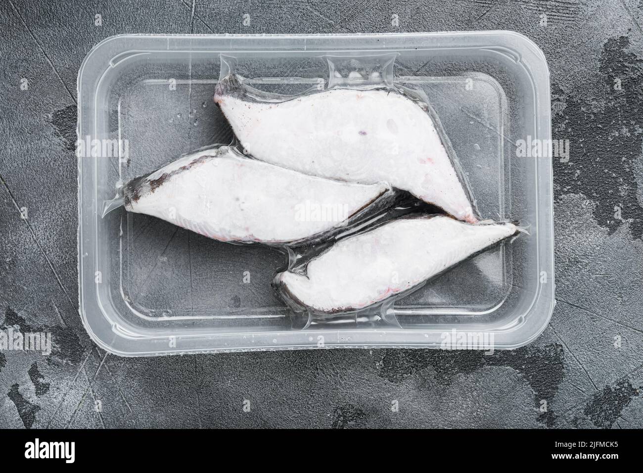 Halibut fish frozen steak pack, on gray stone table background, top ...