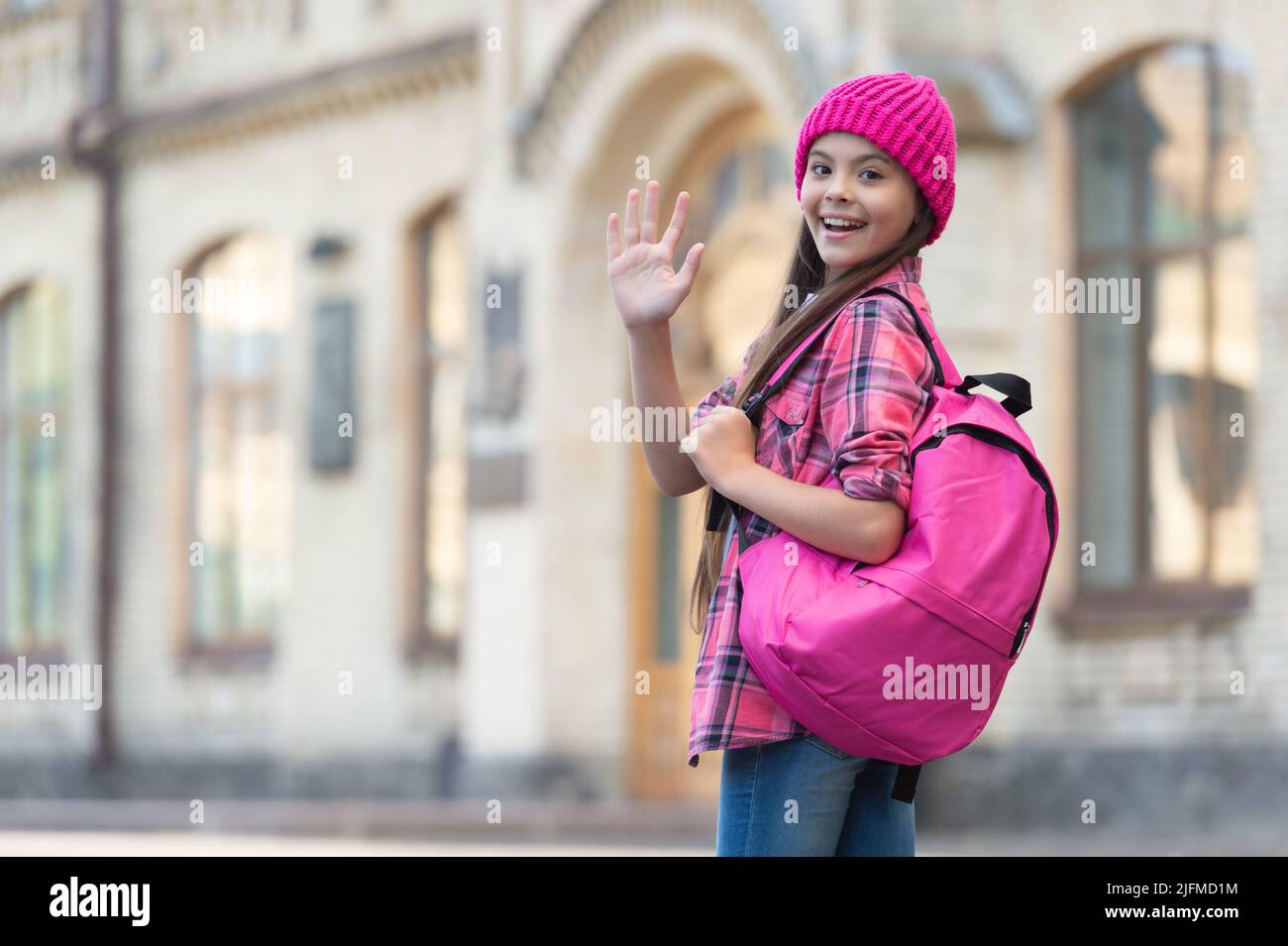 Happy teen girl back-to-school waving hand making hello or goodbye ...