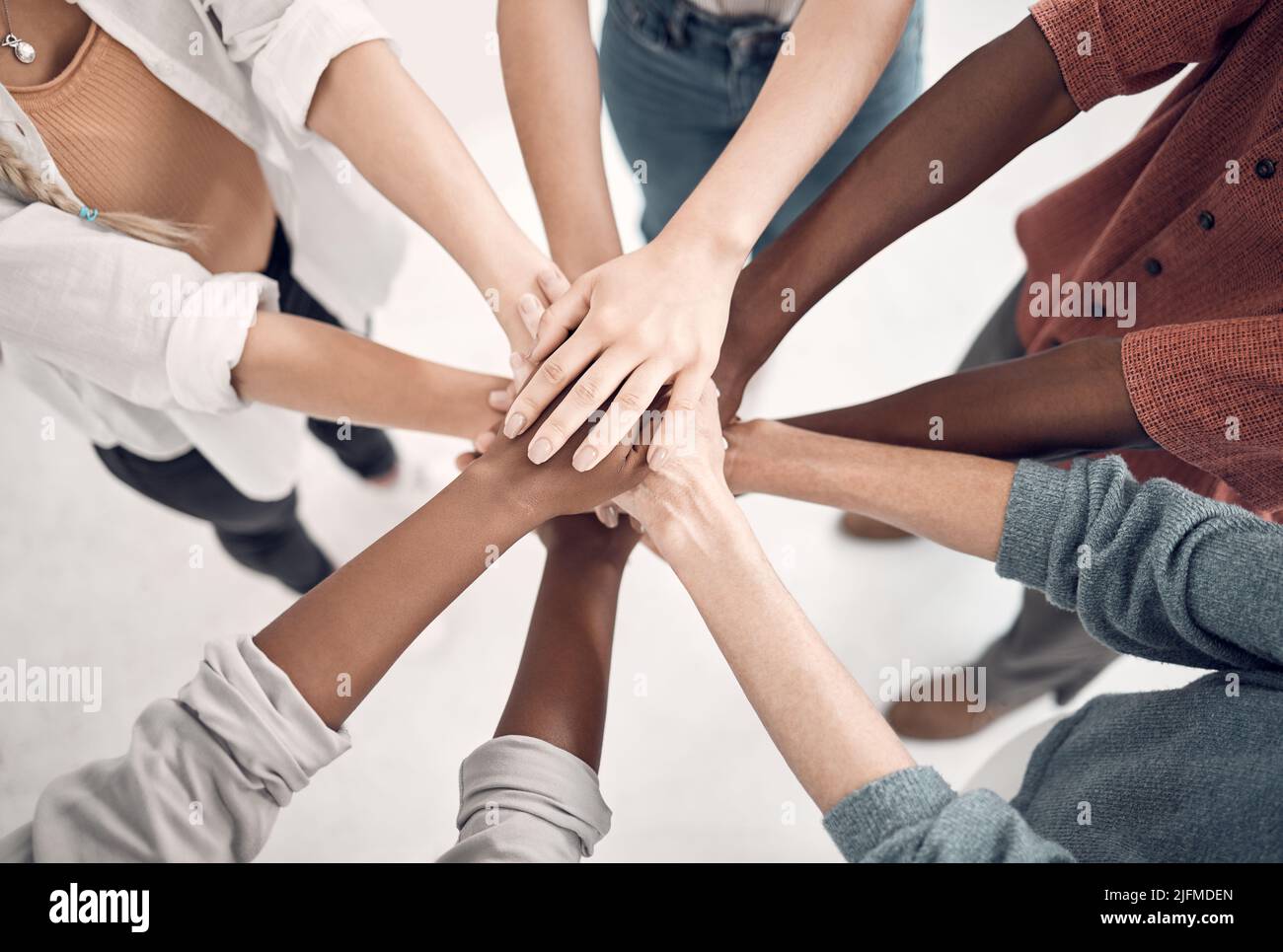 Group of diverse businesspeople piling their hands together in an ...