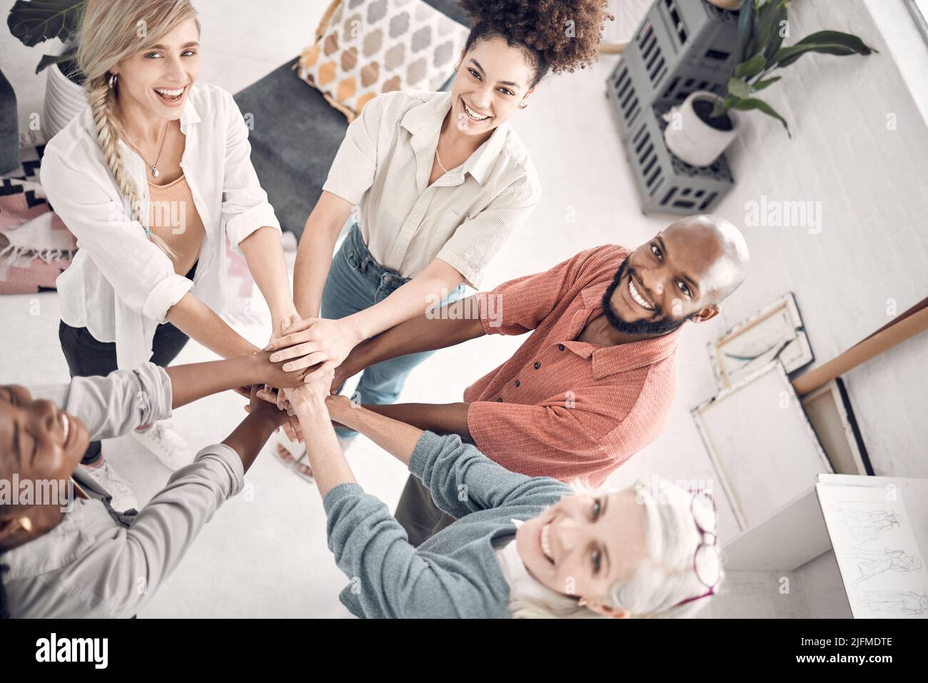 Group of five cheerful diverse businesspeople piling their hands ...