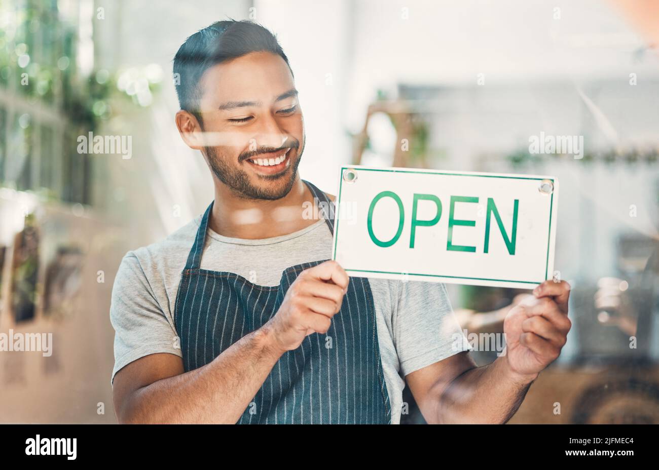 One young hispanic man hanging up an open sign in at a window on ...