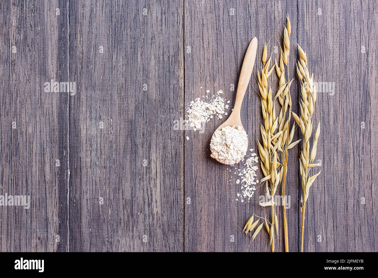 Rolled oats and oat ears of grain on a wooden table, with copy space ...