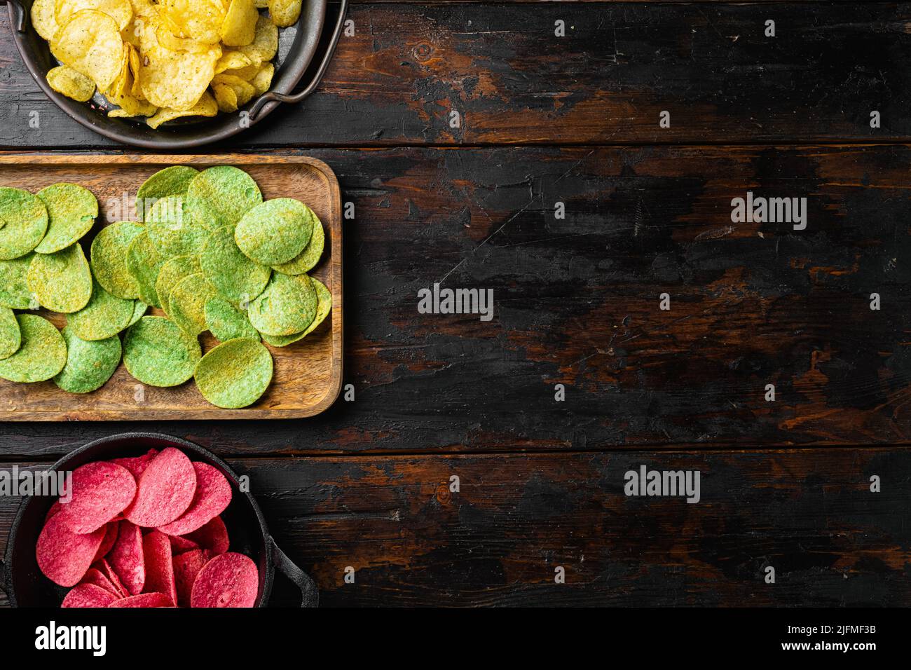 Crispy potato chips on old dark wooden table background, top view flat ...