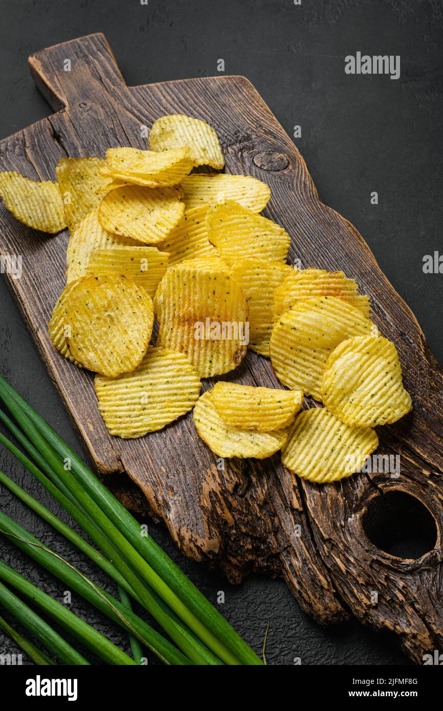 Wavy Potato Chips on black dark stone table background Stock Photo - Alamy