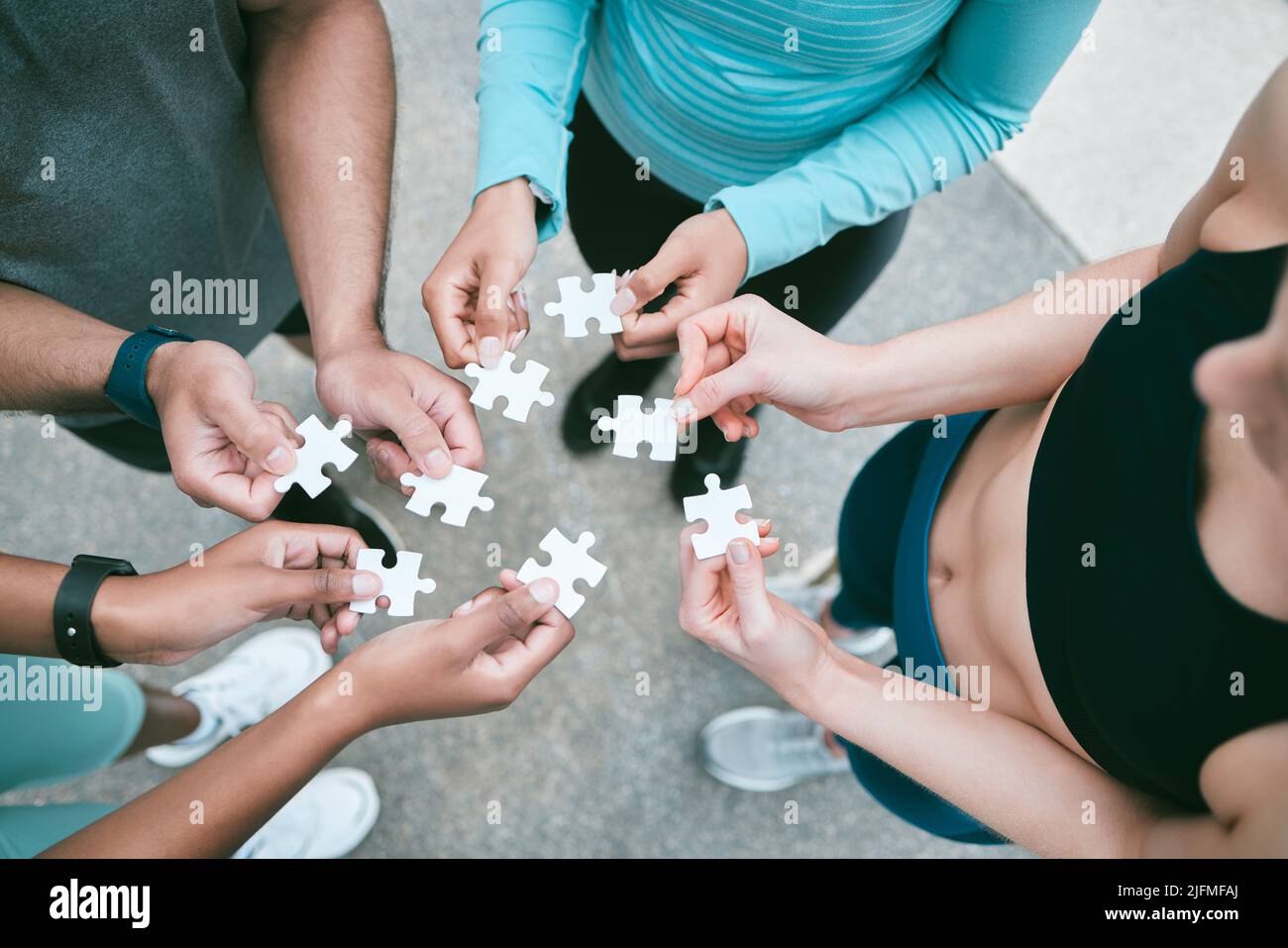 Closeup of diverse group of people from above assembling jigsaw puzzle ...