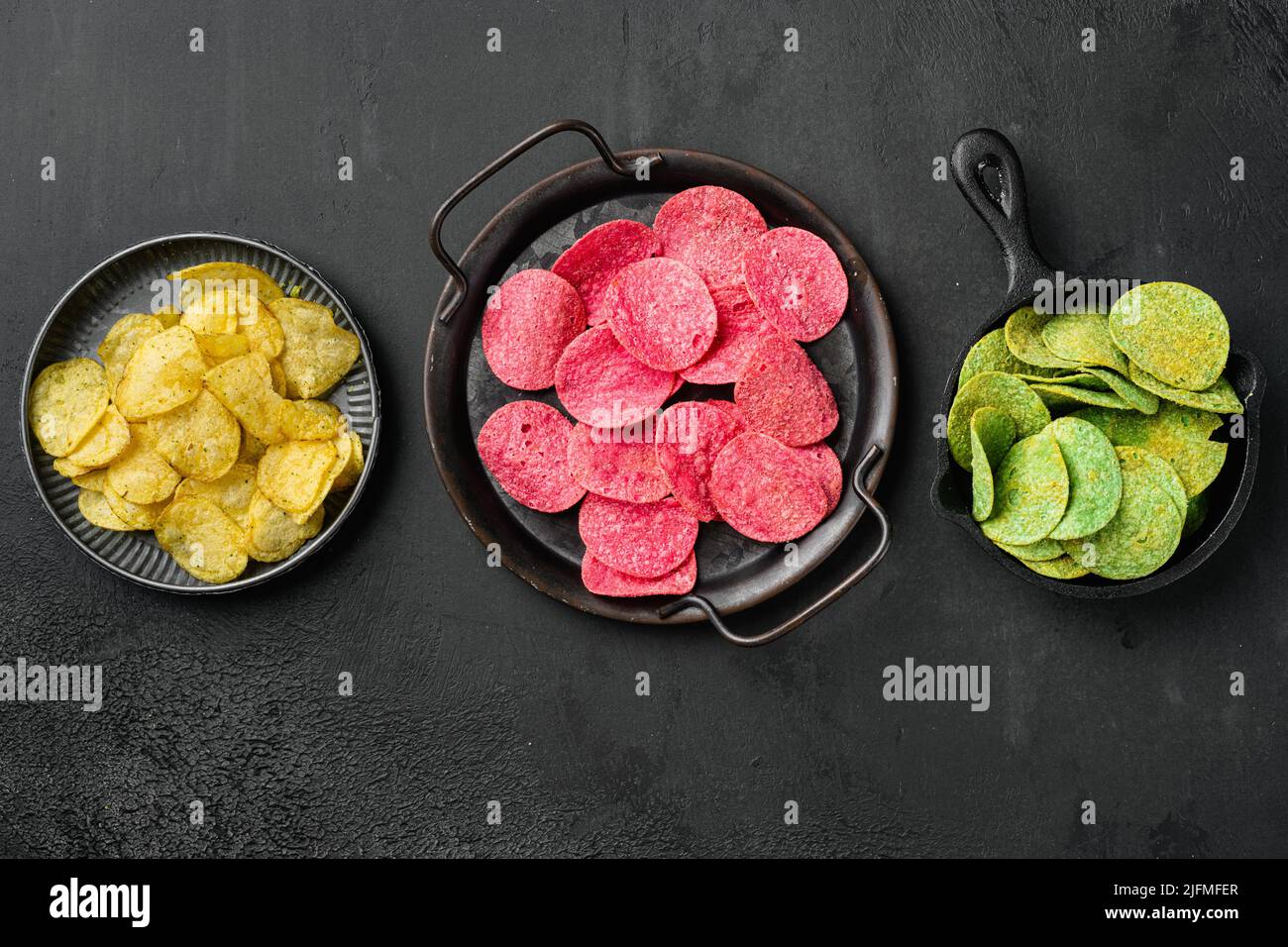 Set potato chips on black dark stone table background, top view flat ...