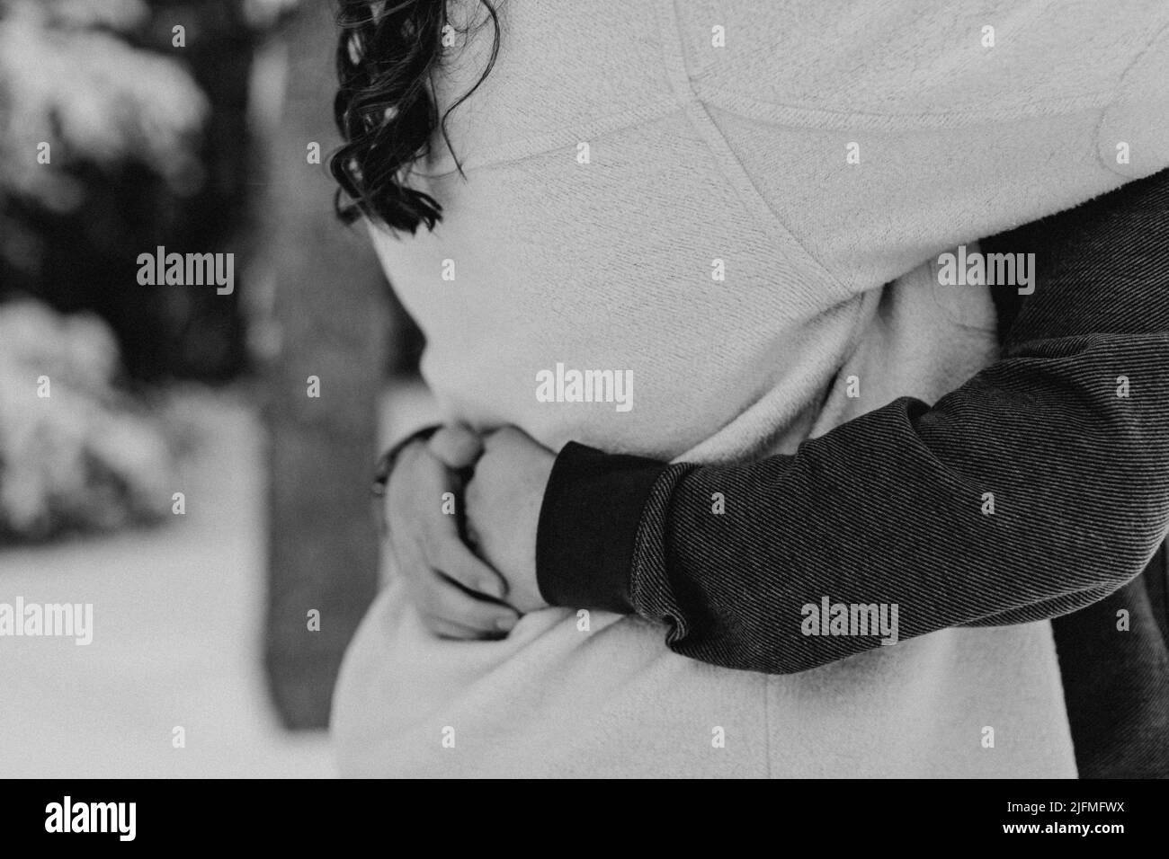 A grayscale shot of male hands hugging a female Stock Photo - Alamy