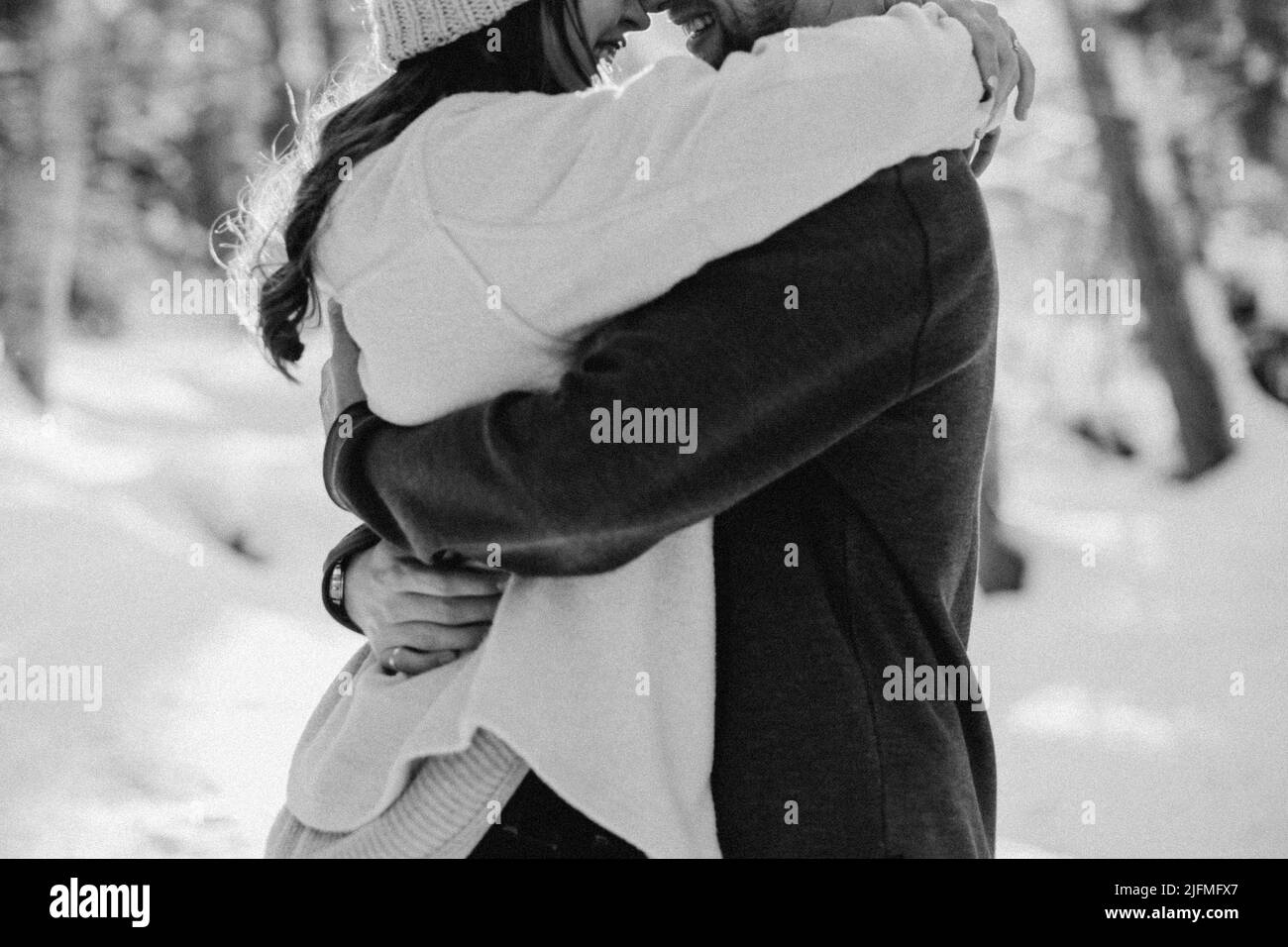 A grayscale shot of a couple hugging outdoors with blur background ...