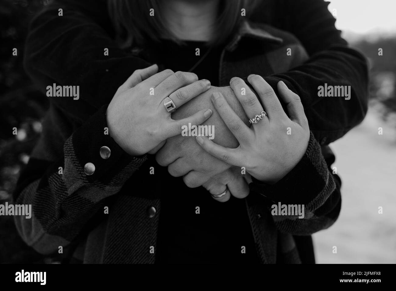 A grayscale shot of male hands hugging a female from back Stock Photo ...