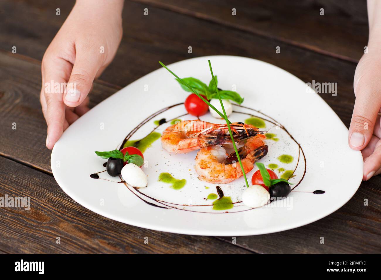 Waiter hands put plate with shrimps on dark table Stock Photo - Alamy