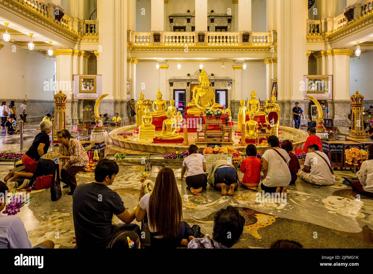 Gold white interior room at Buddhist Temple with people kneeling on the ...