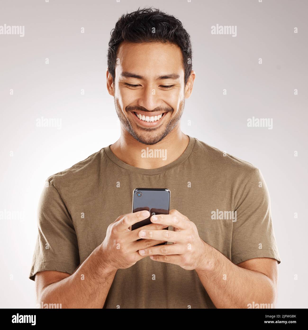 Handsome young mixed race man using his phone while standing in studio ...