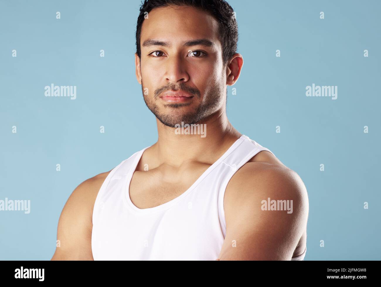 Handsome young hispanic man posing in studio isolated against a blue ...