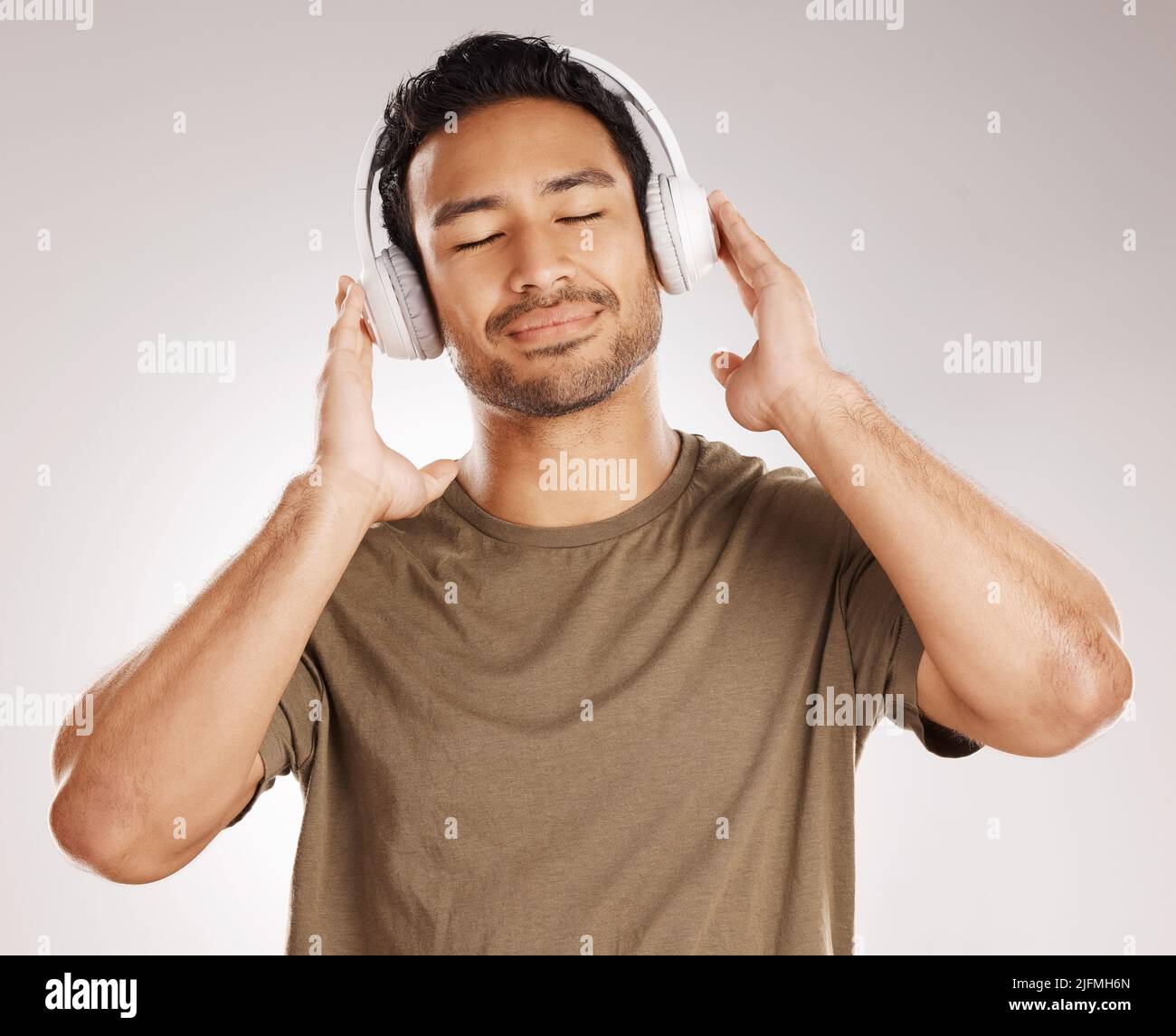Handsome young mixed race man listening to music while standing in ...